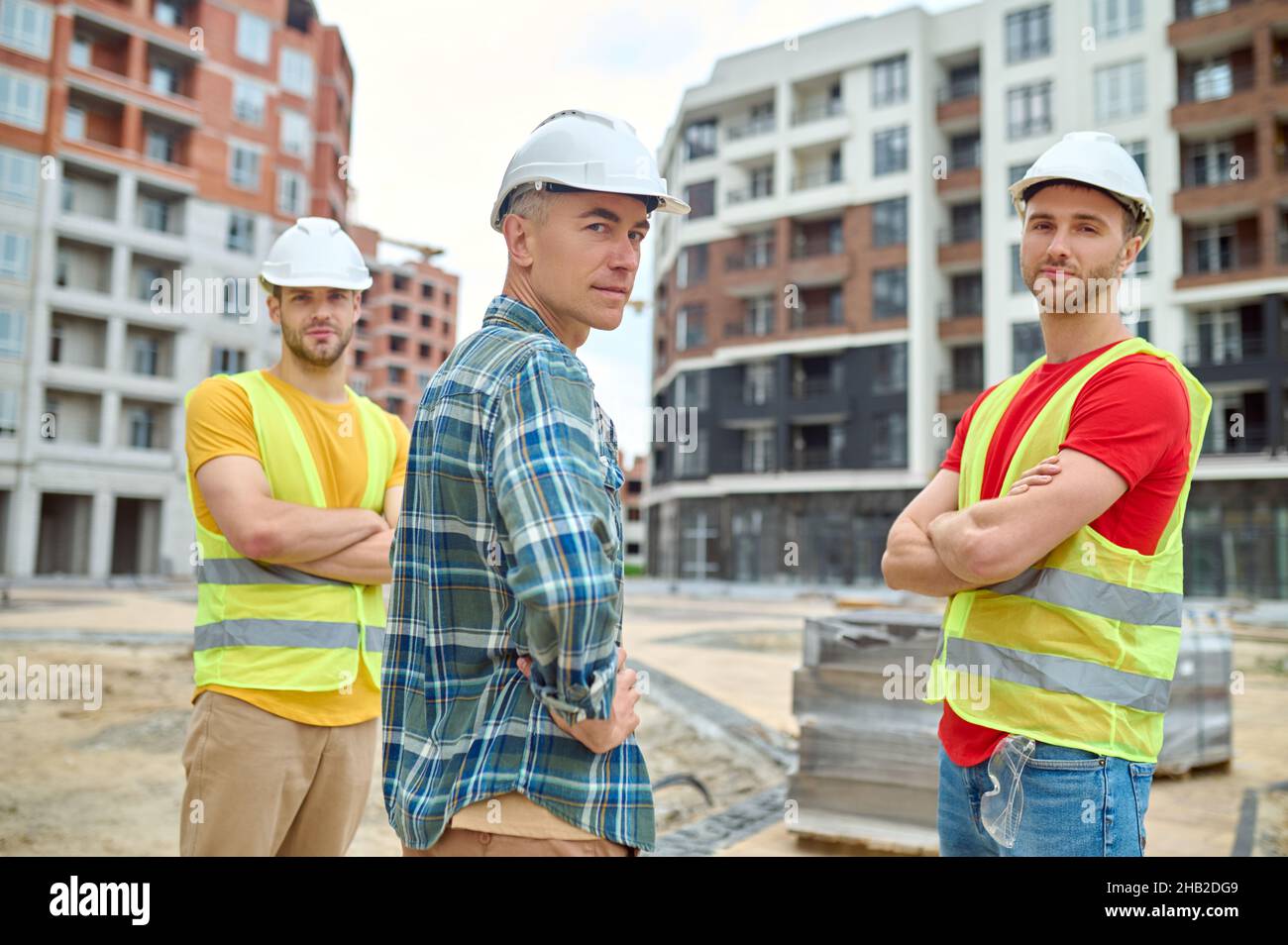 Engineer and two workers looking at camera Stock Photo - Alamy