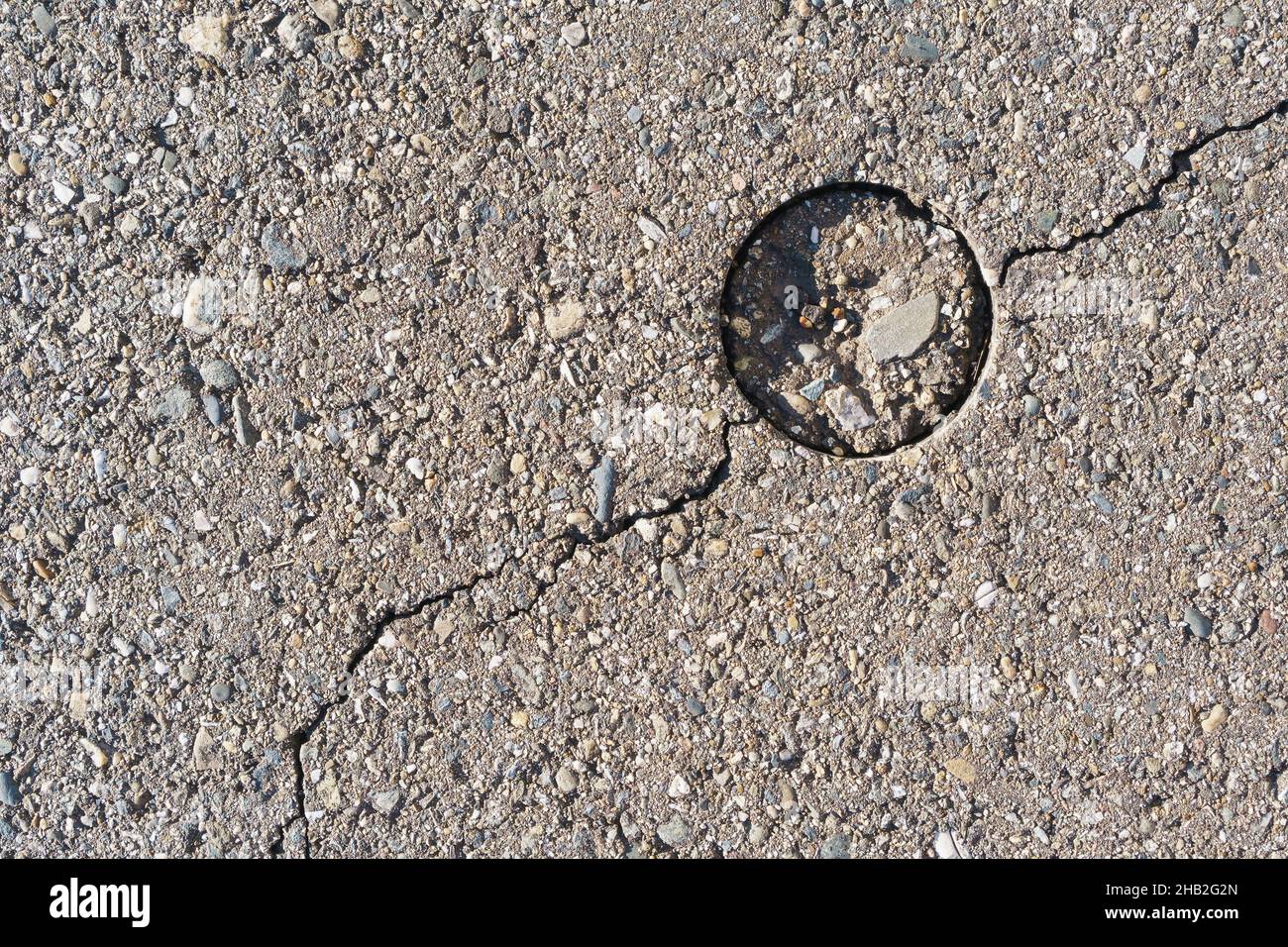 The texture of a concrete road with stones and cracks in full screen ...