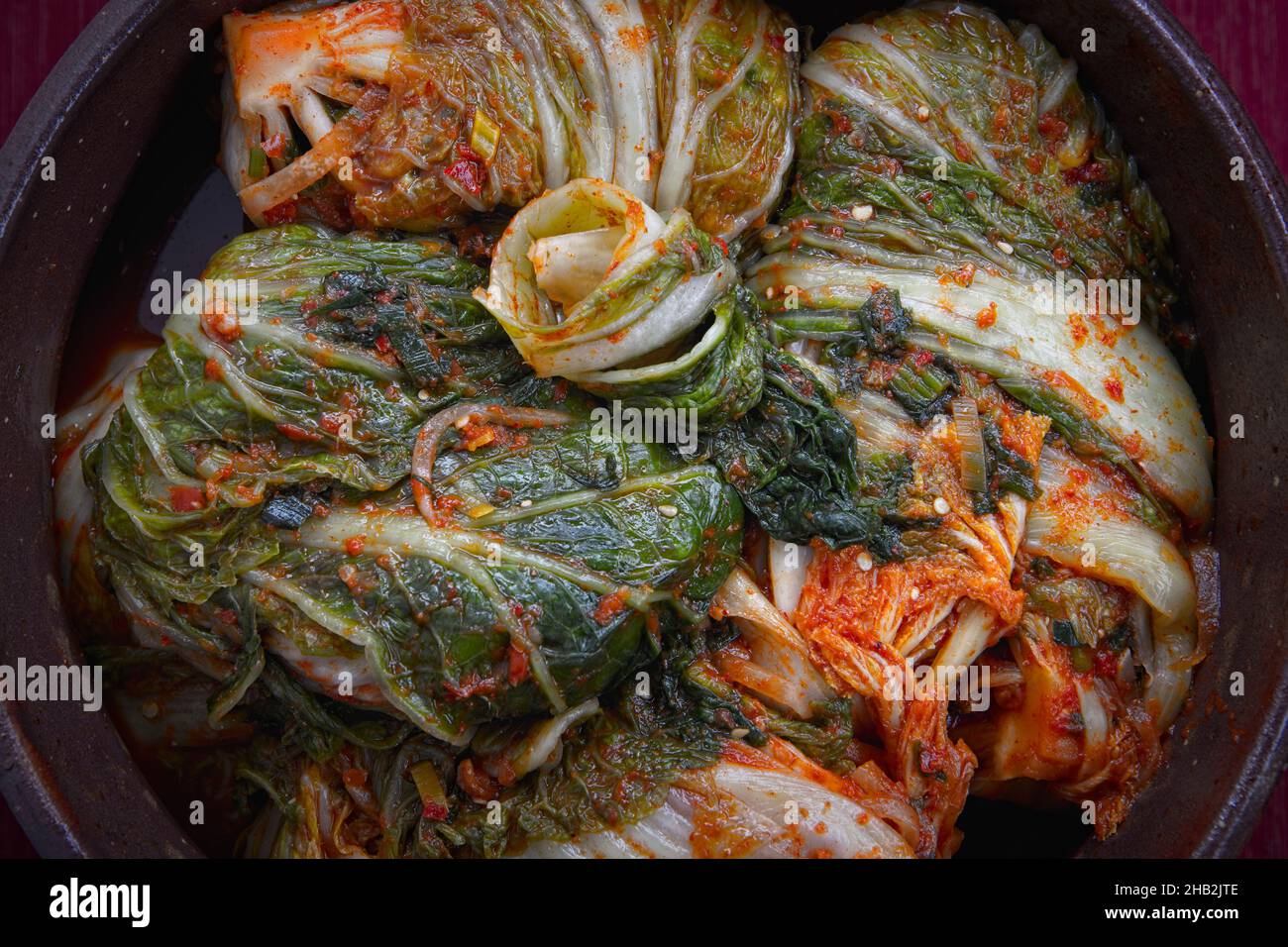 A studio overview of whole kimchi freshly made stacked inside a large ...