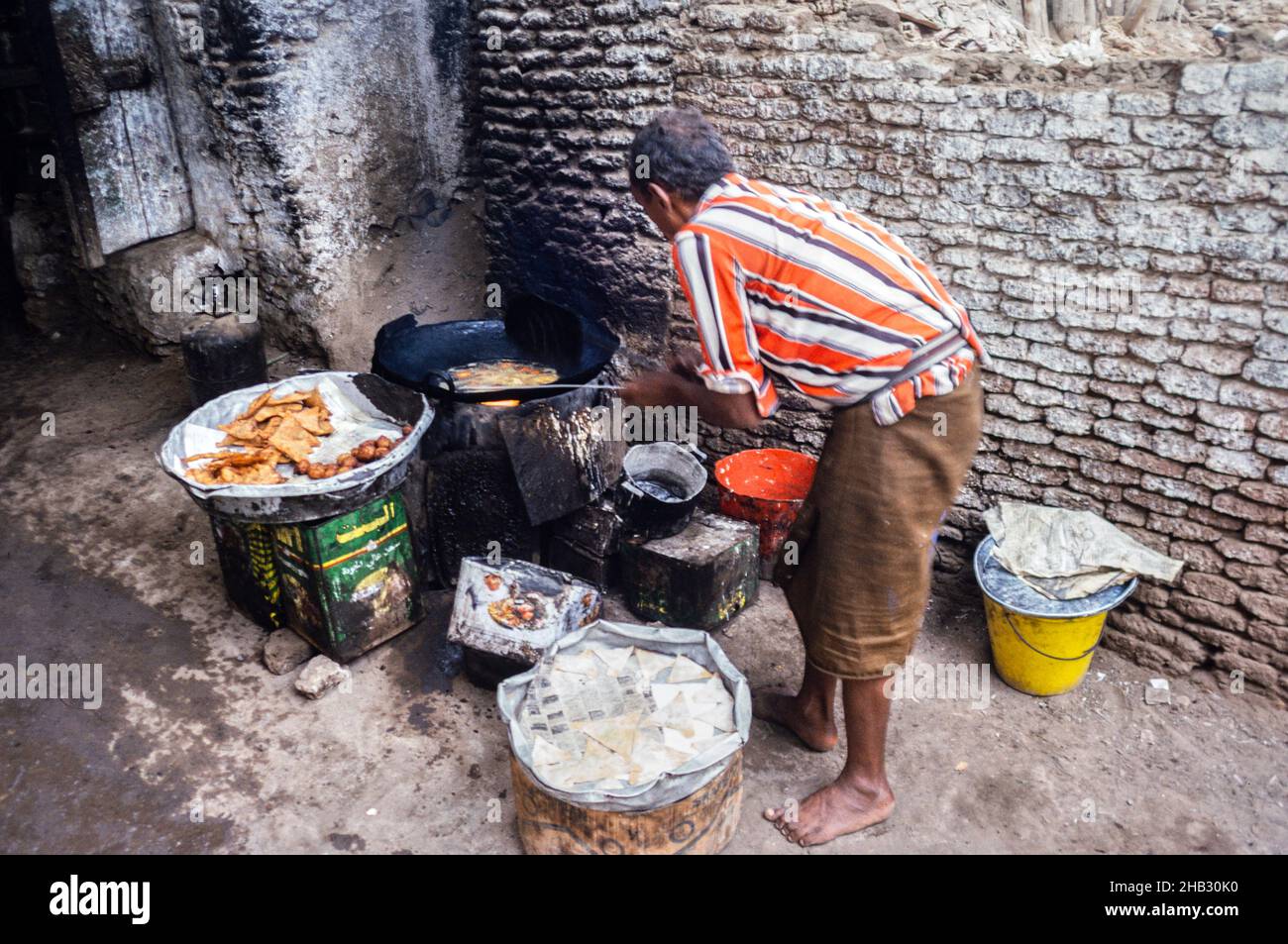 Trader cooking snacks in dark alleyway street in Zebid, Zabid, Yemen ...