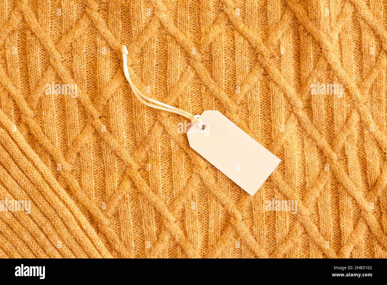 Blank price tag on knitted sweater as background Stock Photo - Alamy