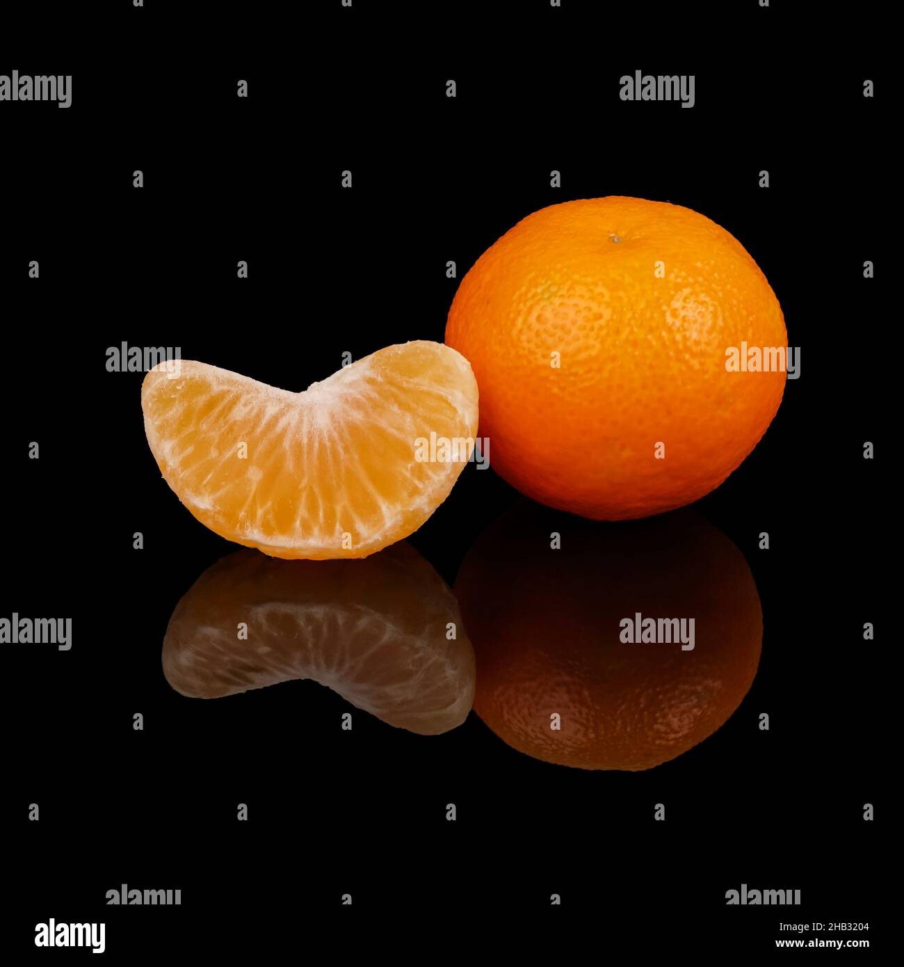 A slice of ripe tangerine and a whole tangerine, on a black background ...