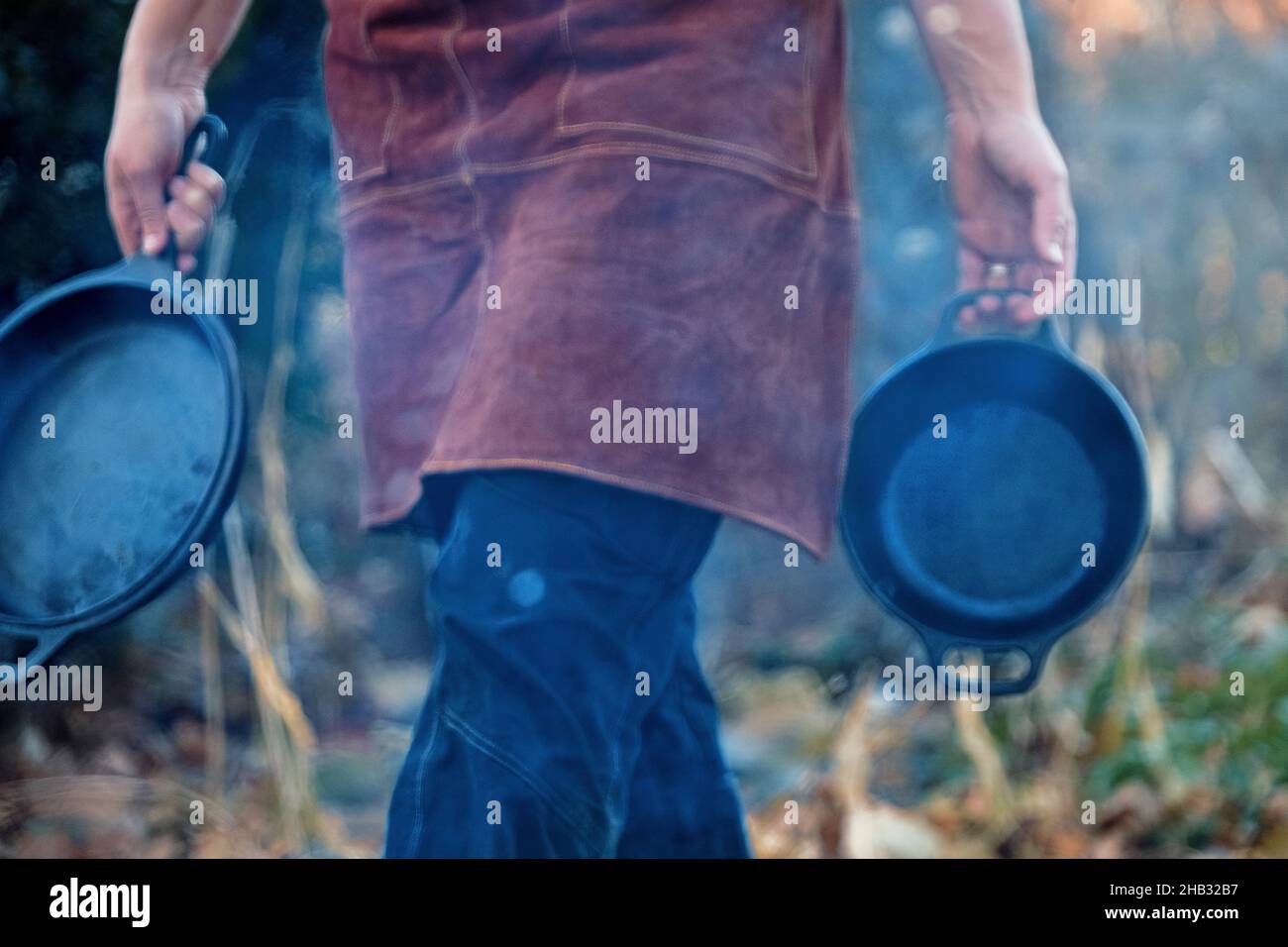 Person carrying two cast iron skillets outdoors Stock Photo - Alamy