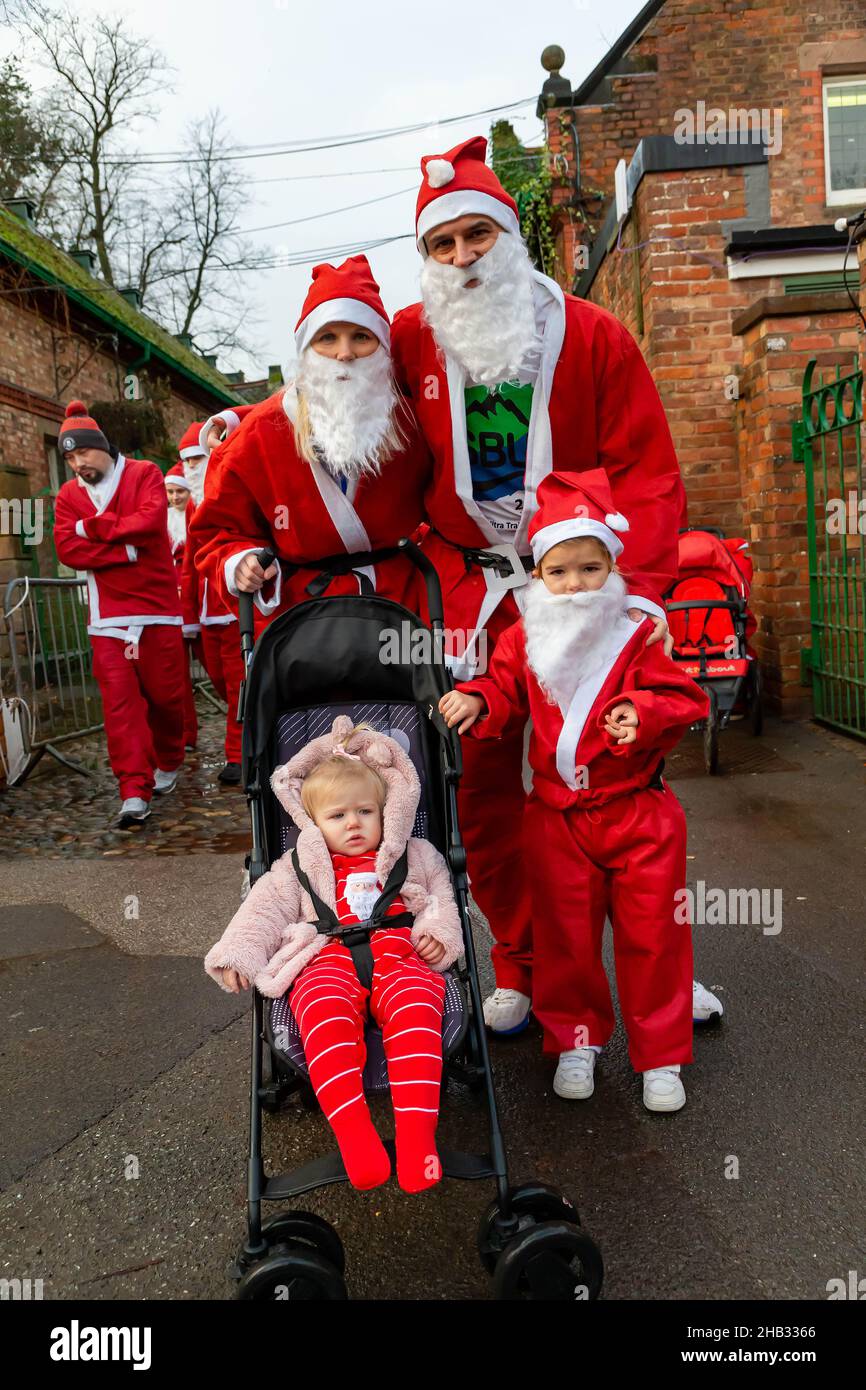 A family of Santa's pose with child in buggy before a Santa Dash Stock ...