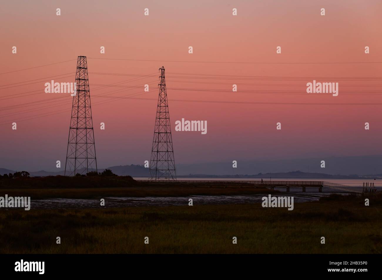 High voltage pylons against a blue and pink ombre sky Stock Photo - Alamy