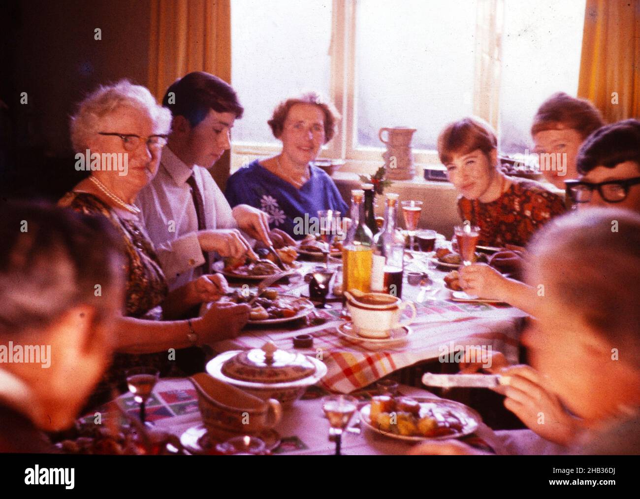 Traditional family Christmas meal all sitting around table eating and ...