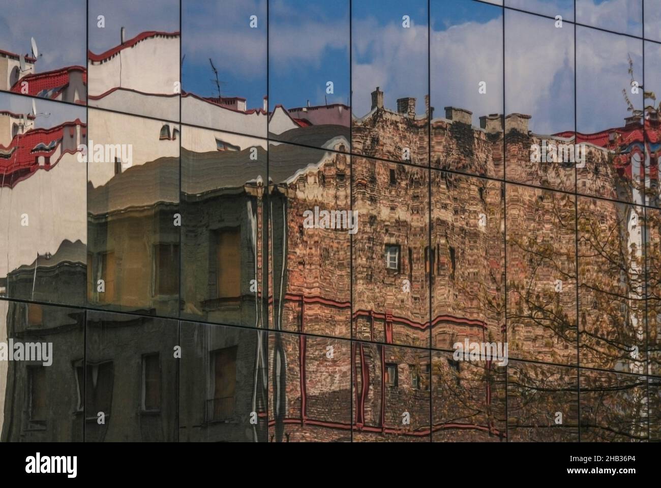 Old desolated tenement house reflected in glass wall of modern office ...