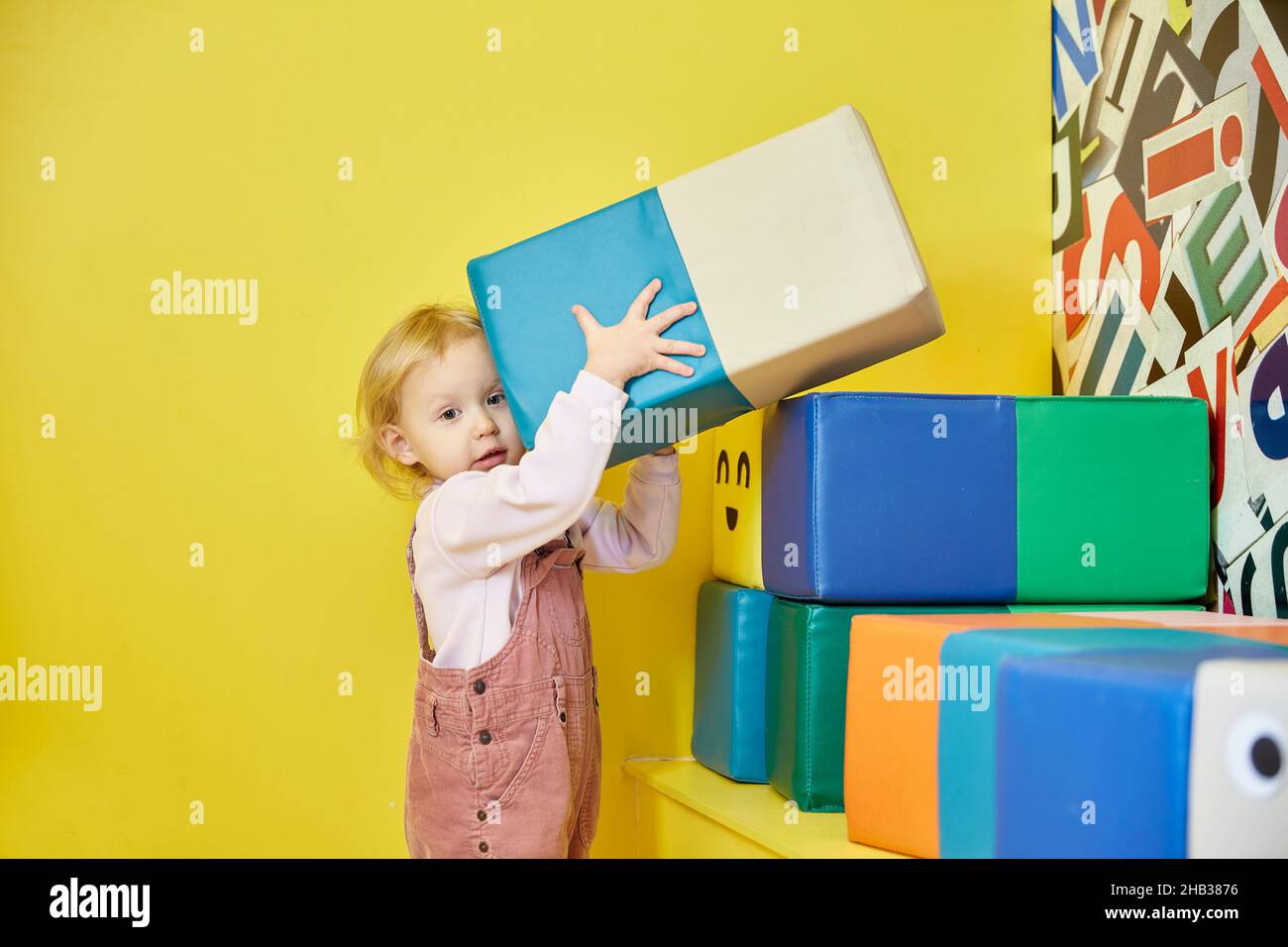 smiling child builds a house out of large soft cubes. Copy space Stock ...