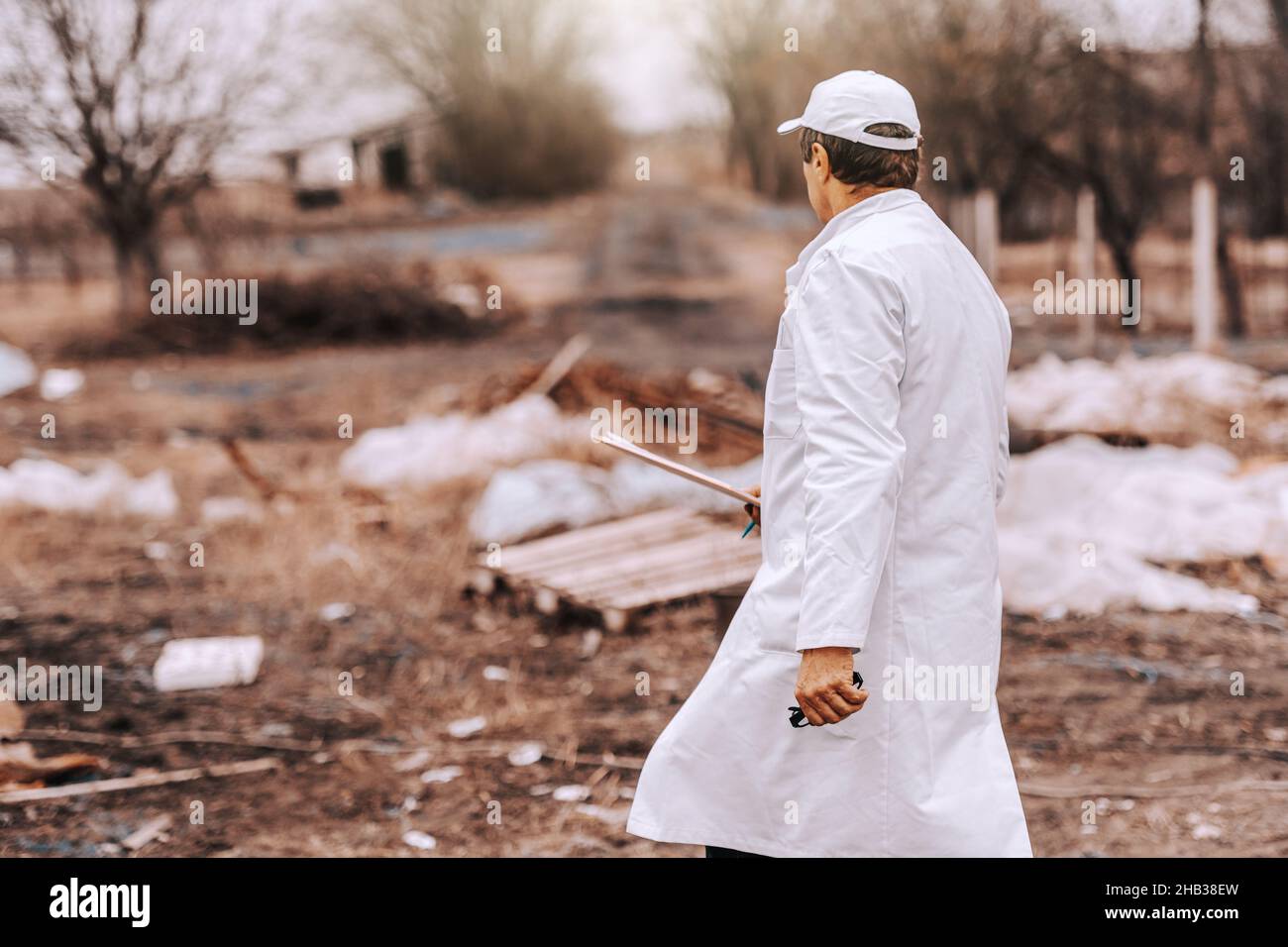 Ecologist in white uniform and cap on head holding clipboard while ...