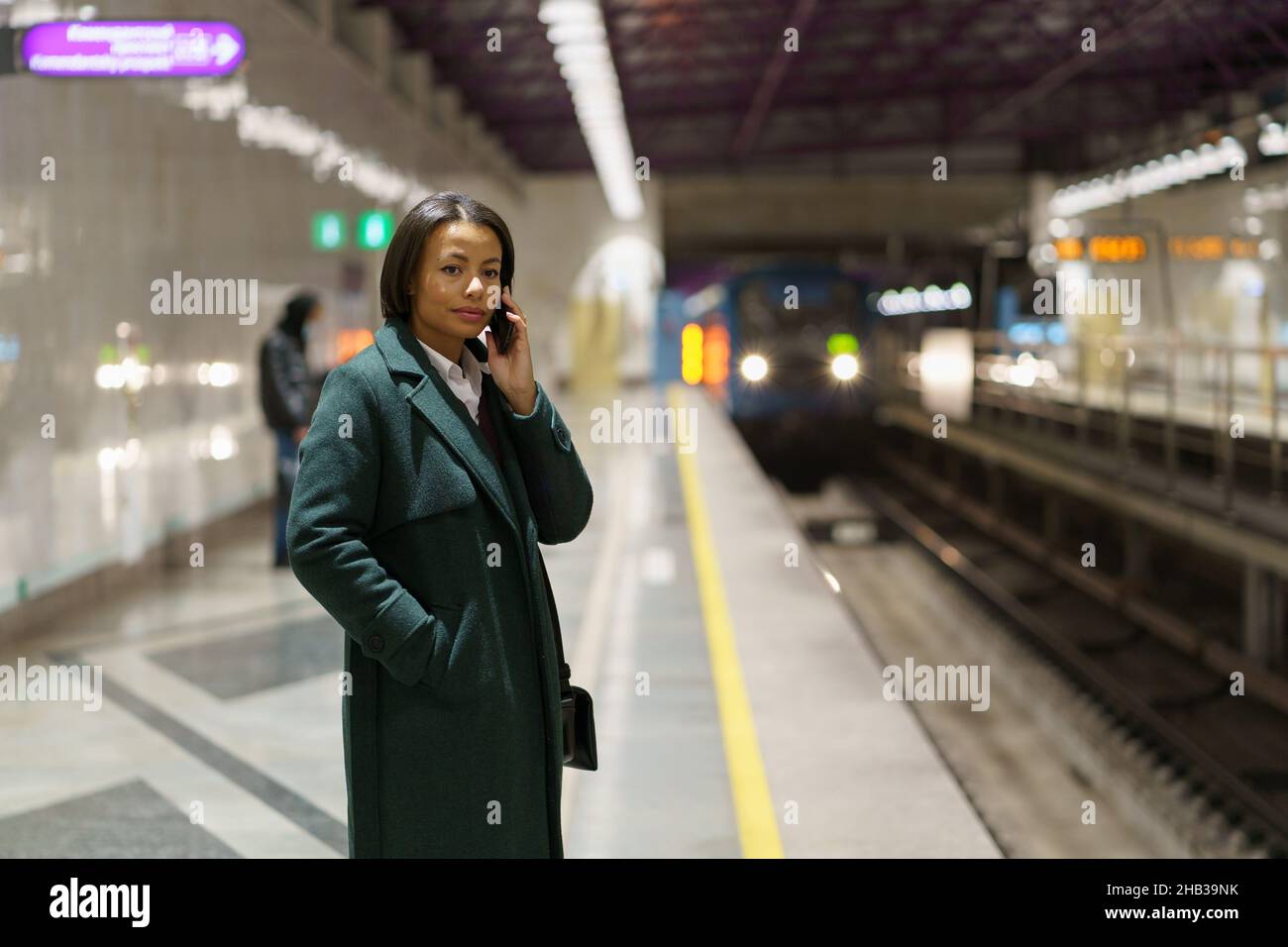 Young african american woman making mobile phone call while waiting for ...