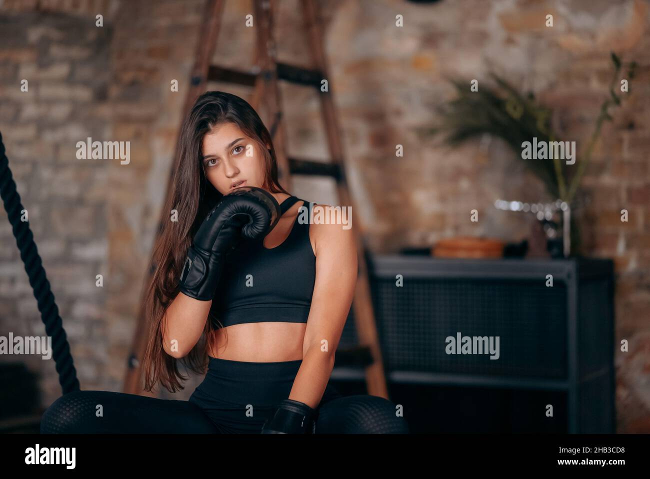Beautiful young fitness girl posing at camera in black boxing glove ...