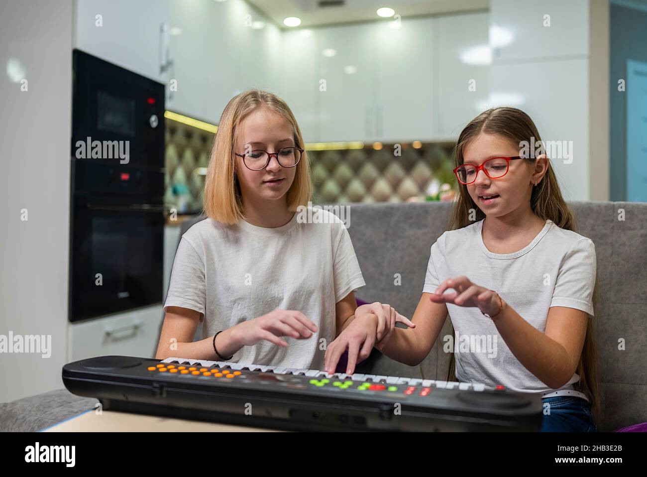 two teenage girls learning to play the piano Stock Photo - Alamy