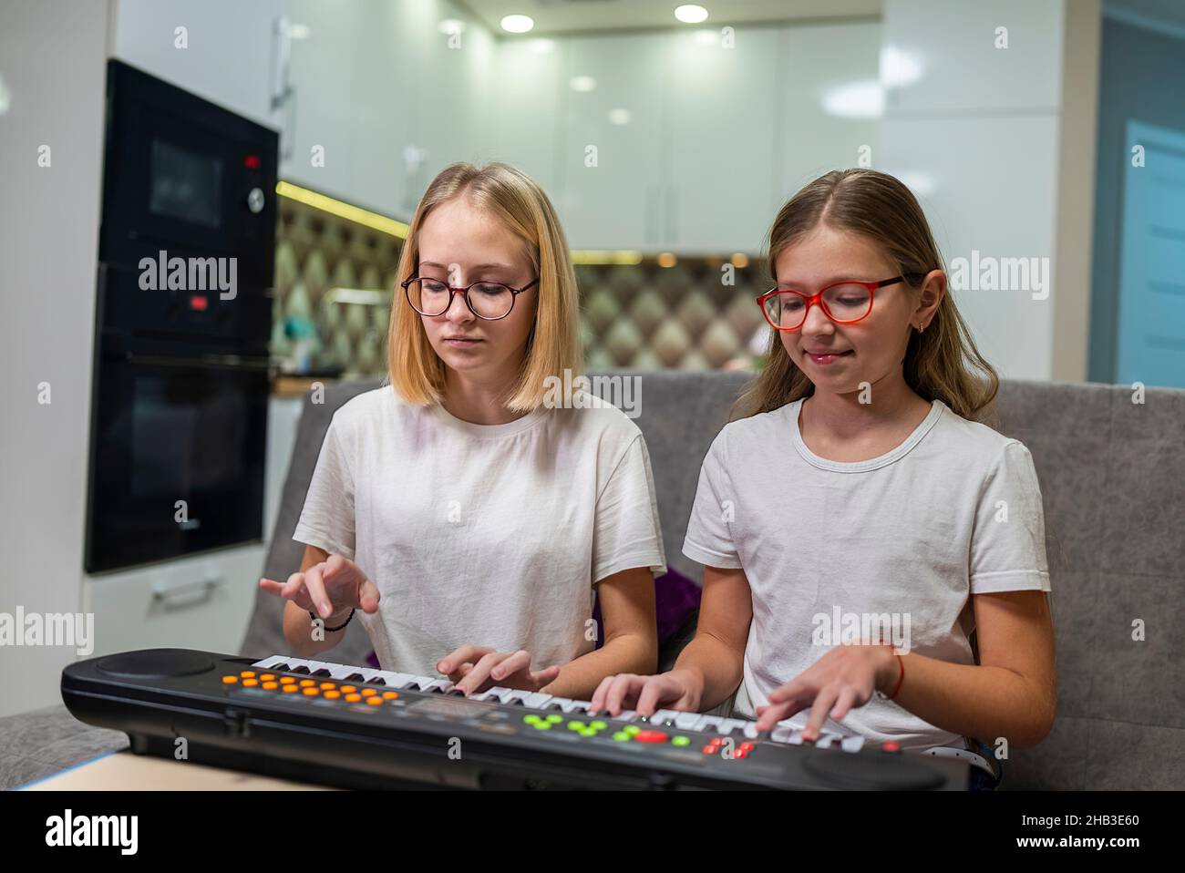 two teenage girls learning to play the piano at home Stock Photo - Alamy