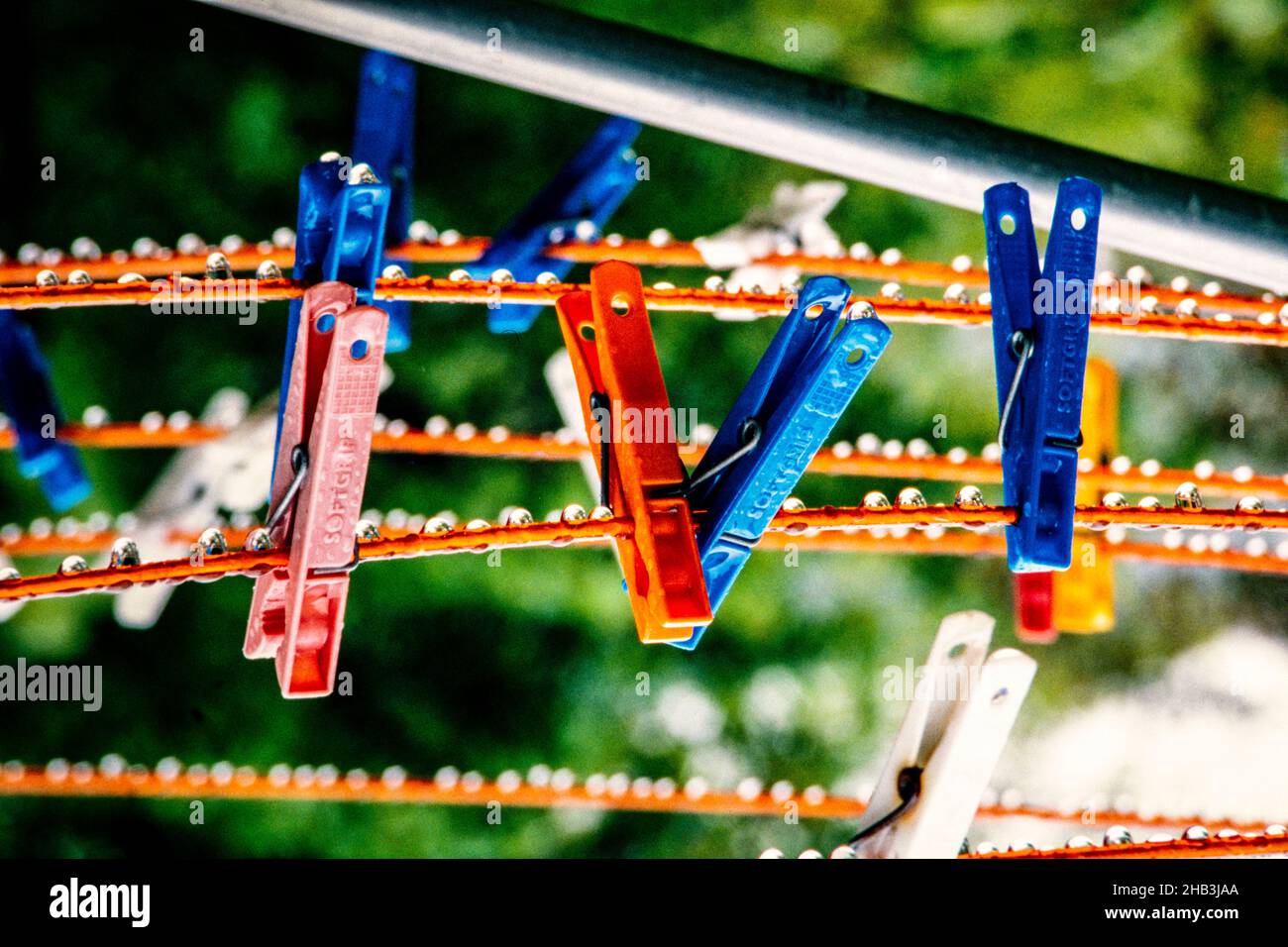 Outdoor close up still life of colourful clothes pegs on a line after ...