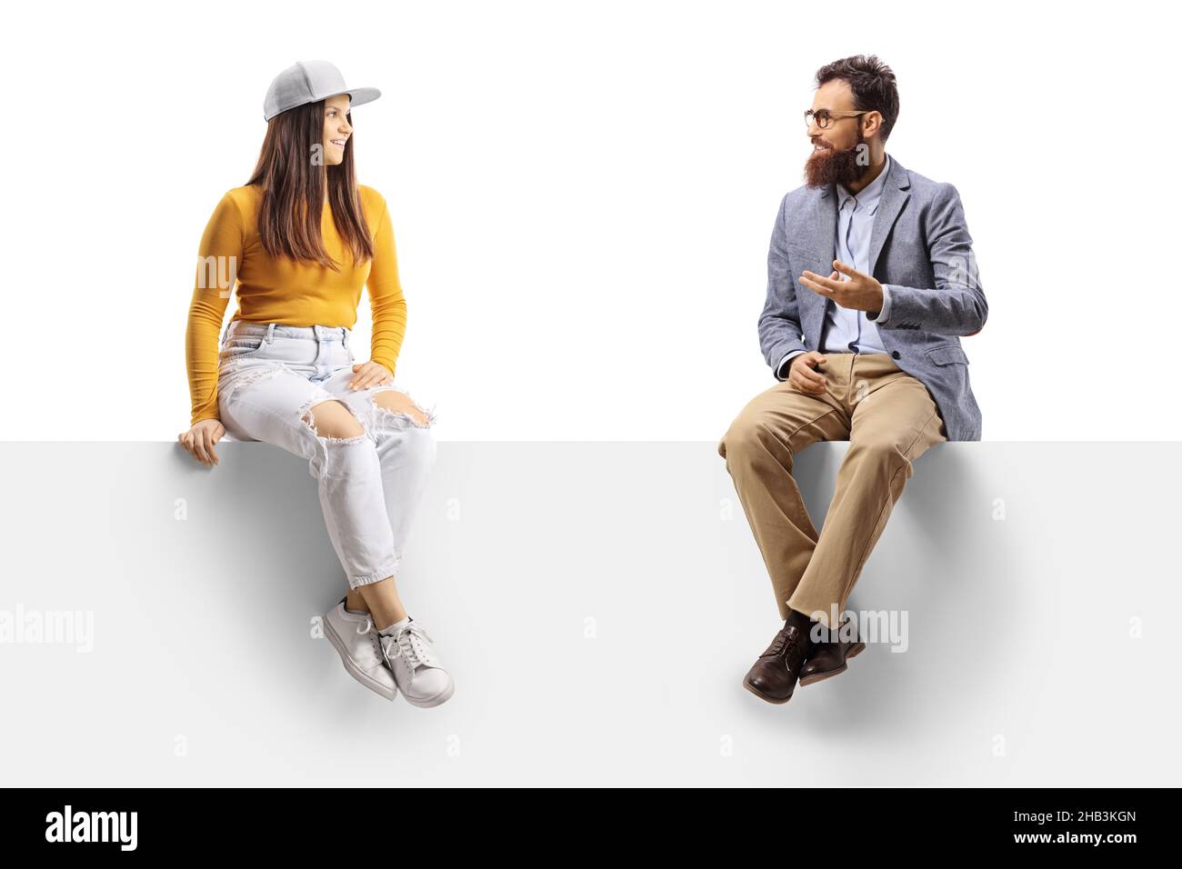 Bearder man talking to a young casual female seated on a blank panel ...