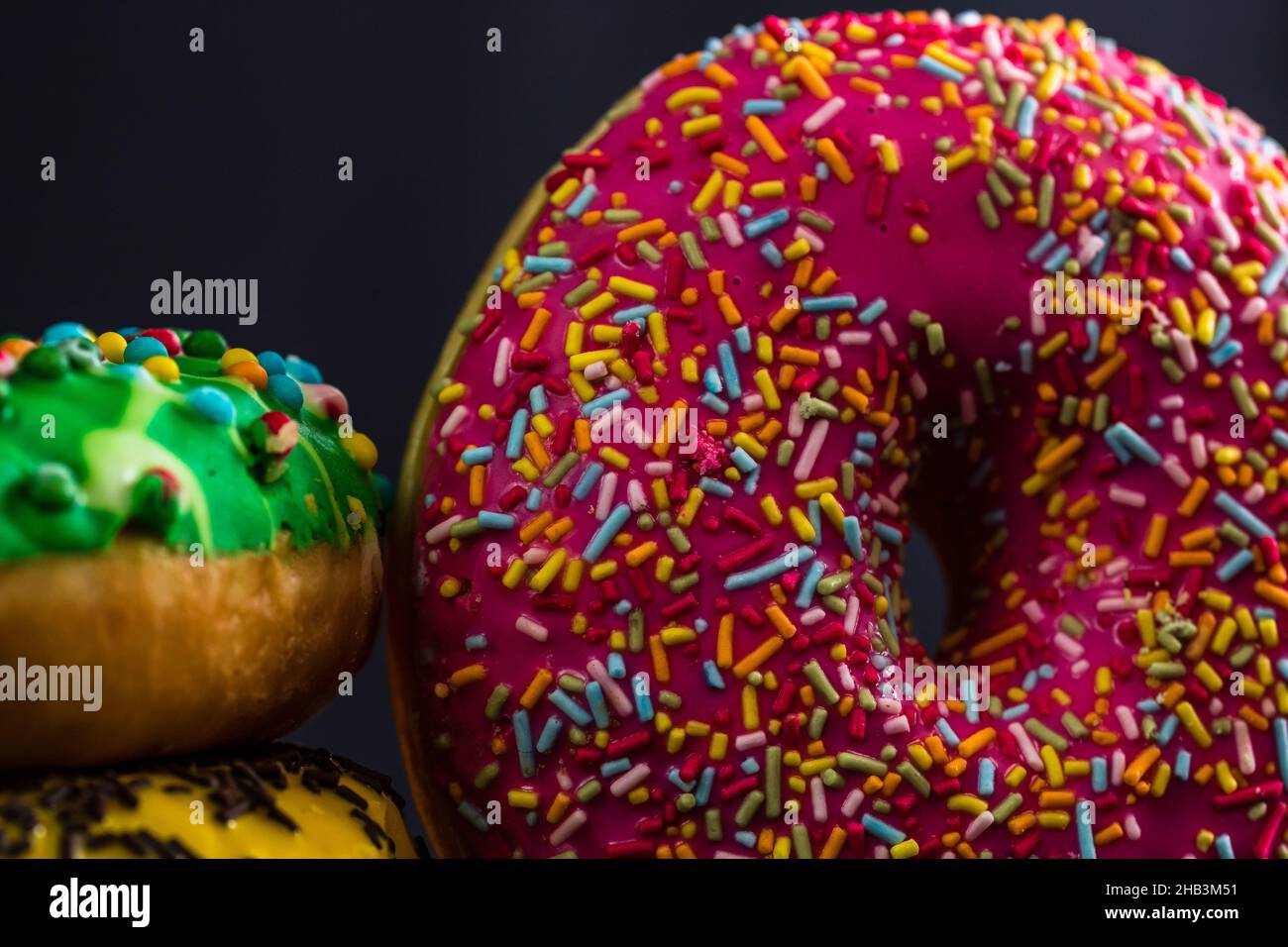 Closeup shot of colorful donuts with sprinkles isolated on a black background Stock Photo - Alamy