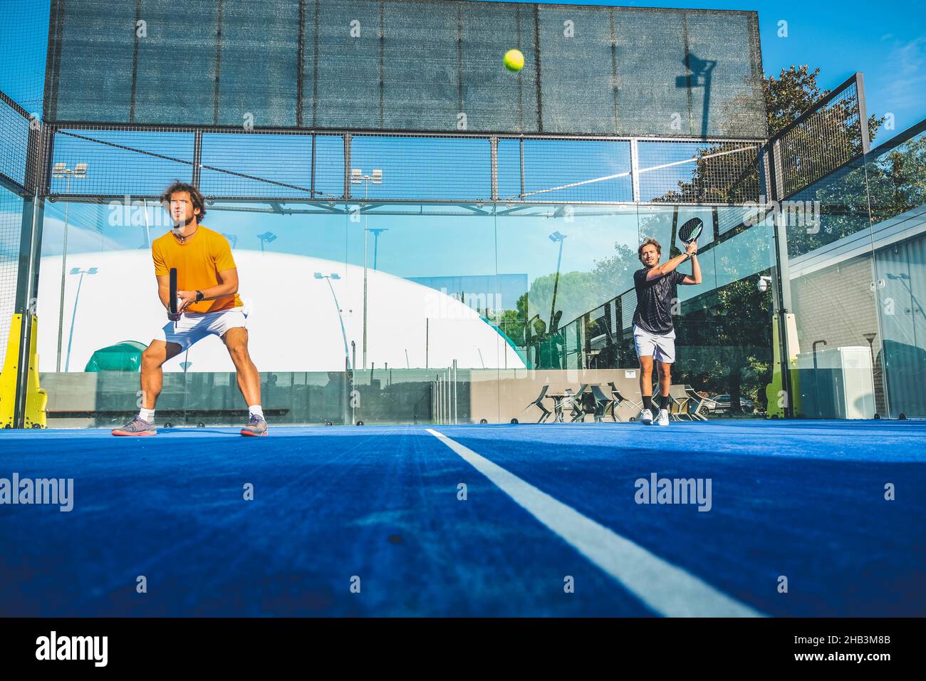 Mixed padel match in a blue grass padel court - Beautiful girl and ...