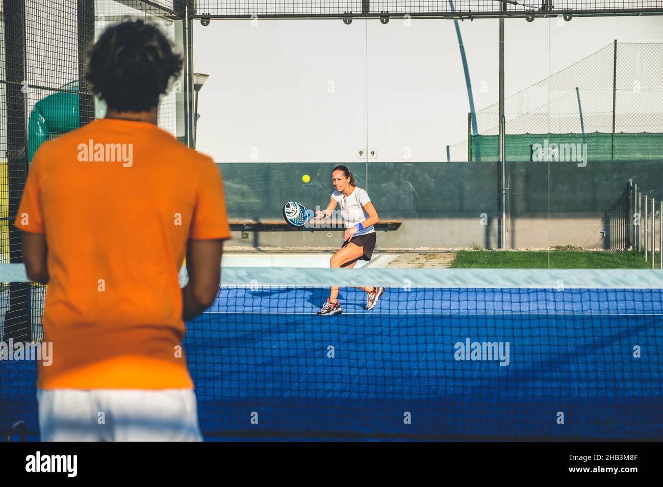 Mixed padel match in a blue grass padel court - Beautiful girl and ...
