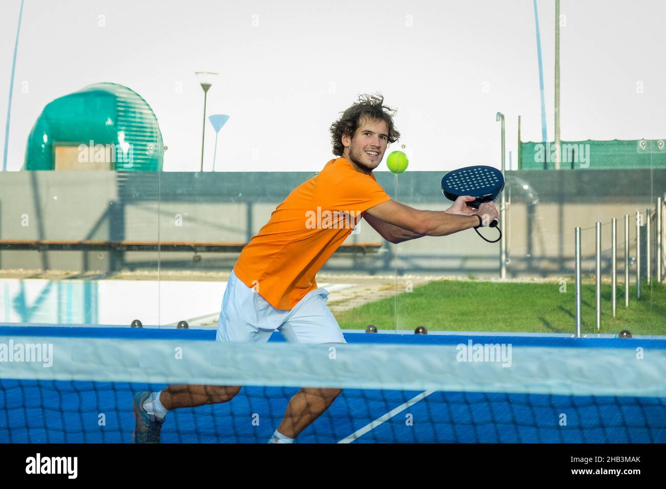 Padel match in a blue grass padel court - Handsome boy player playing a ...