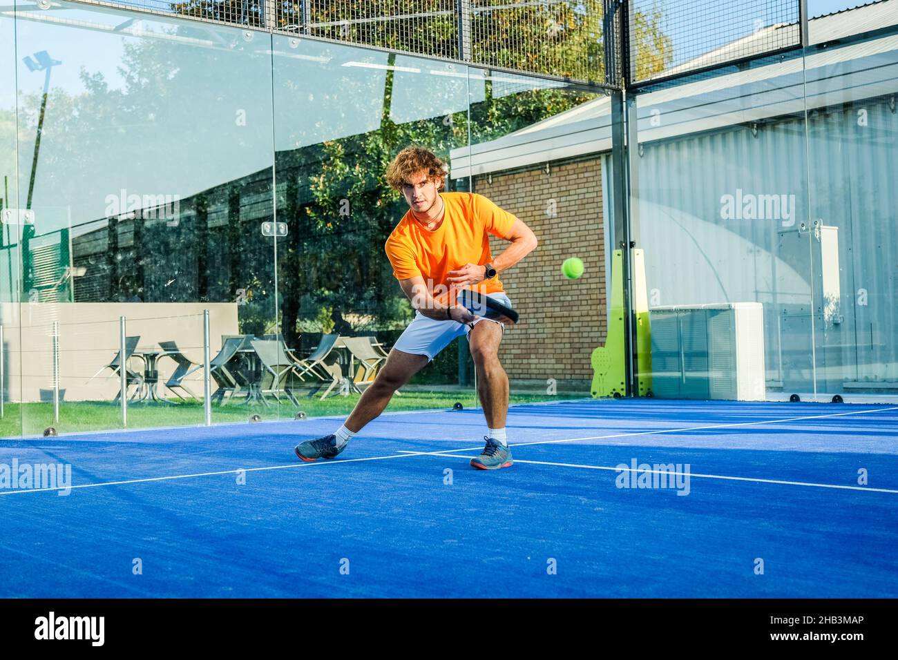 Padel match in a blue grass padel court - Handsome boy player playing a ...