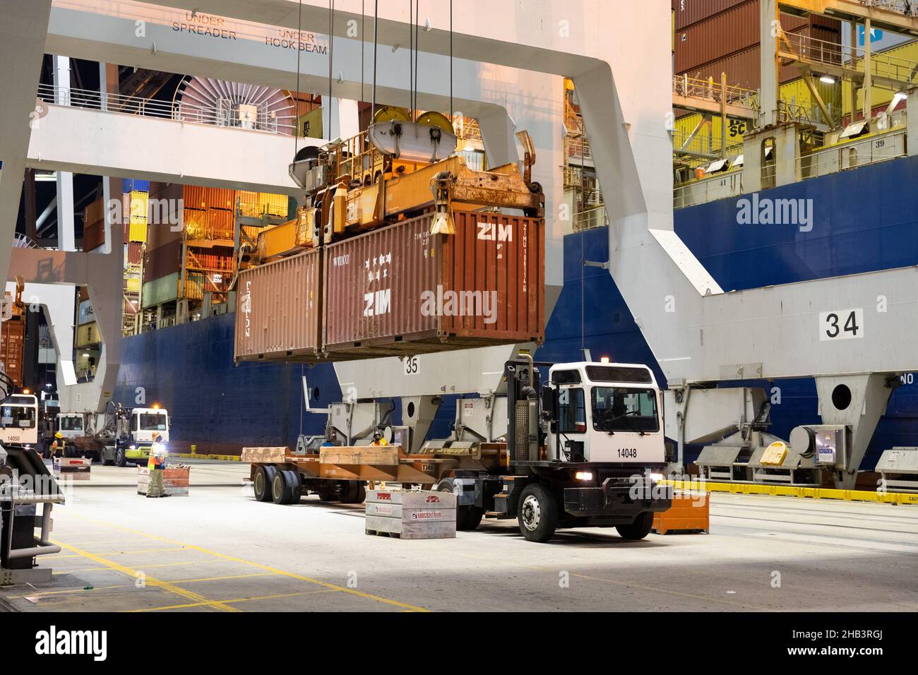 Containers are lifted off a container ship by quay cranes in the ...