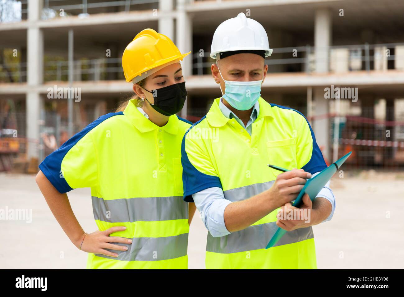 Man and woman engineers in face mask standing in construction site ...