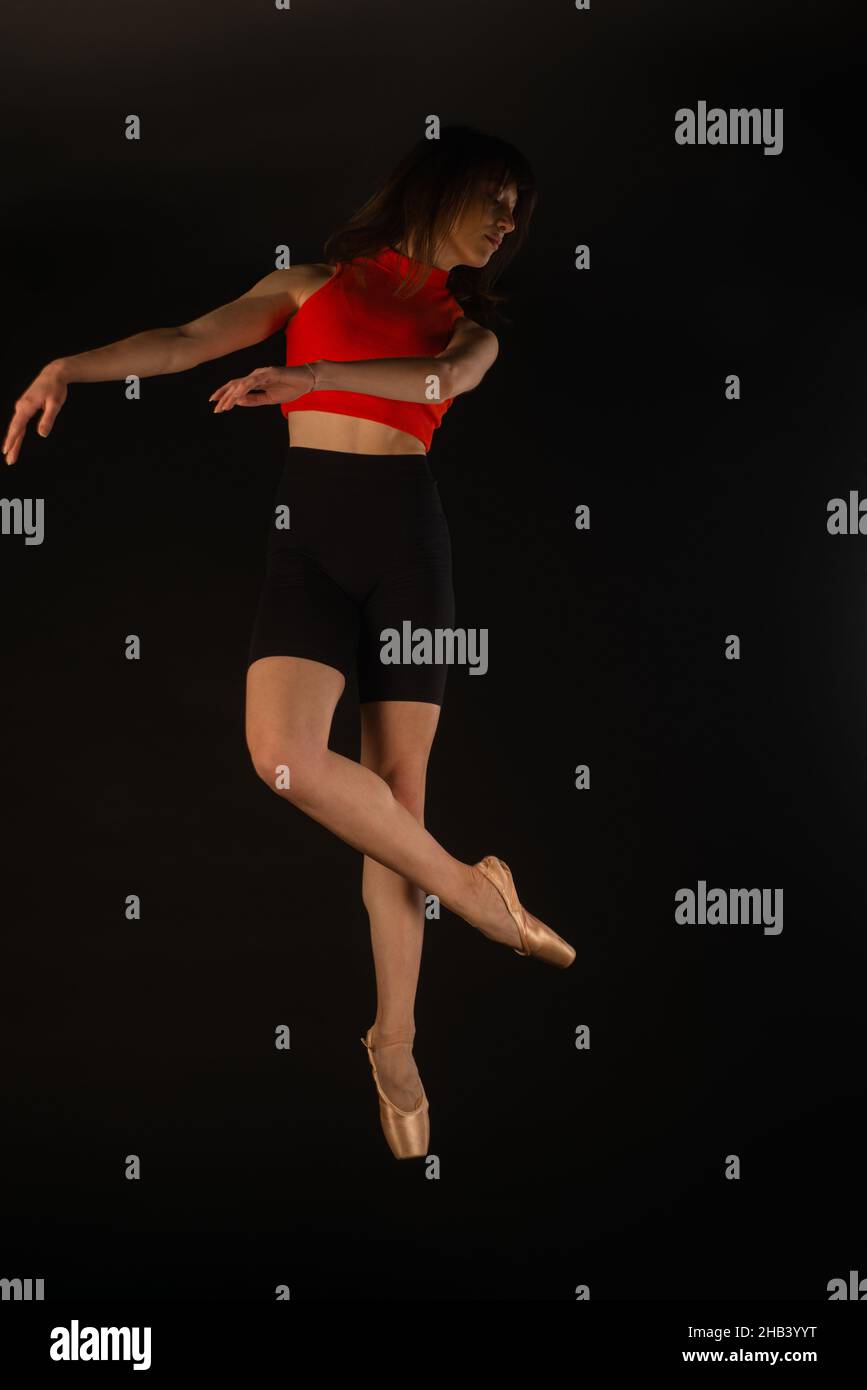 Ballerina is doing some ballet jumping in the studio while posing in ...
