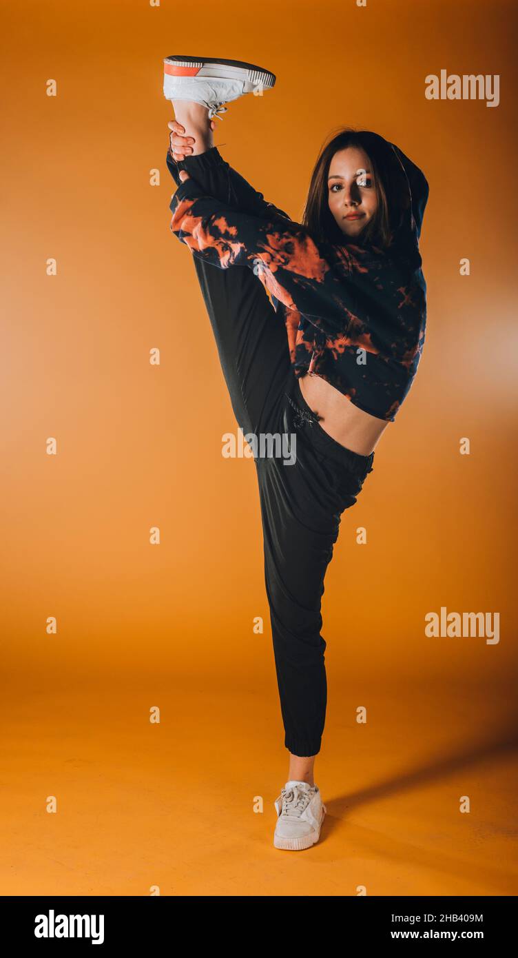 Fit young girl dancer performing a dance routine in the orange studio ...