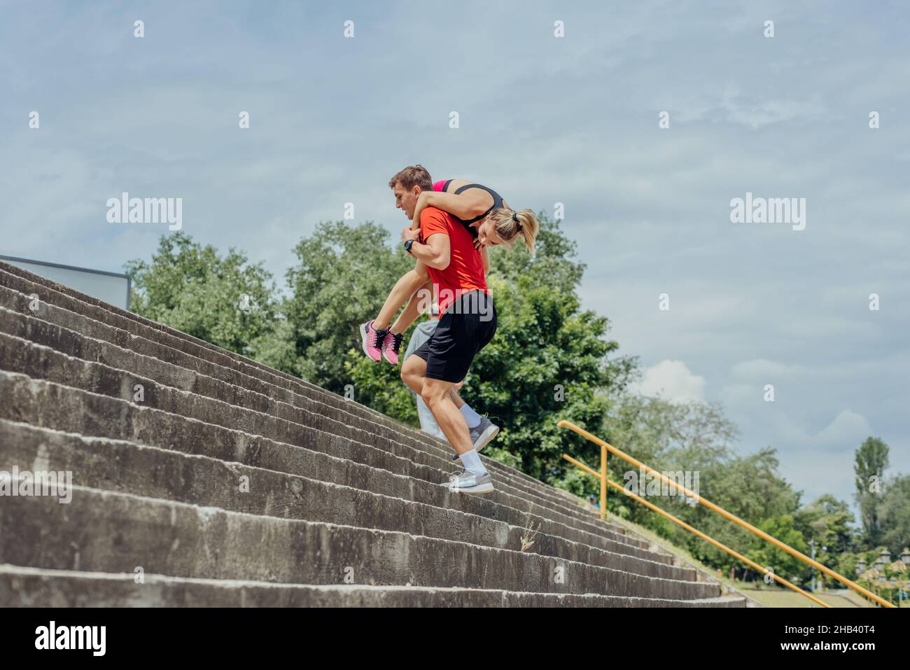 Male athlete carrying his female workout partner on his shoulders while ...