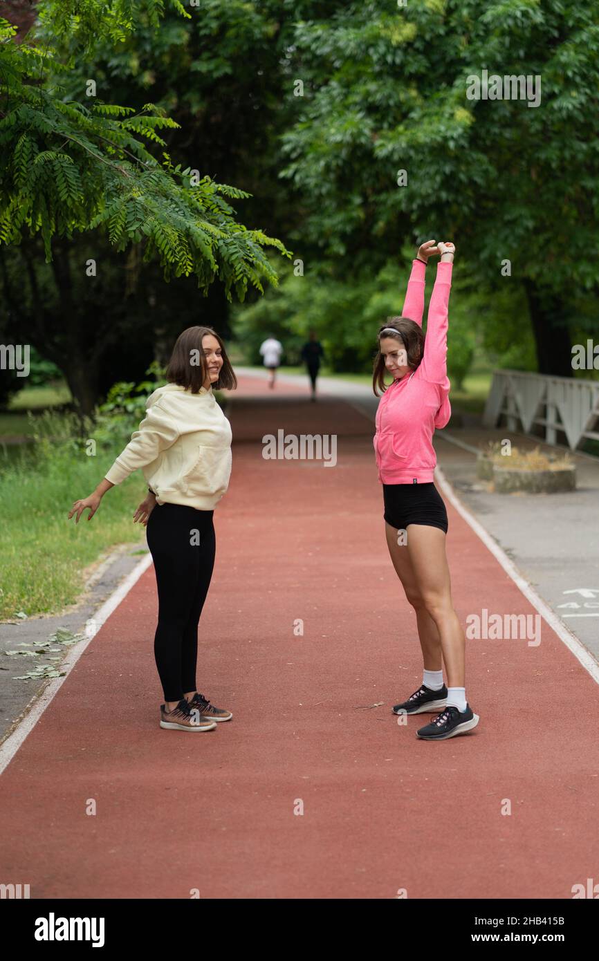 Two attractive girls are stretching their hands before the training ...