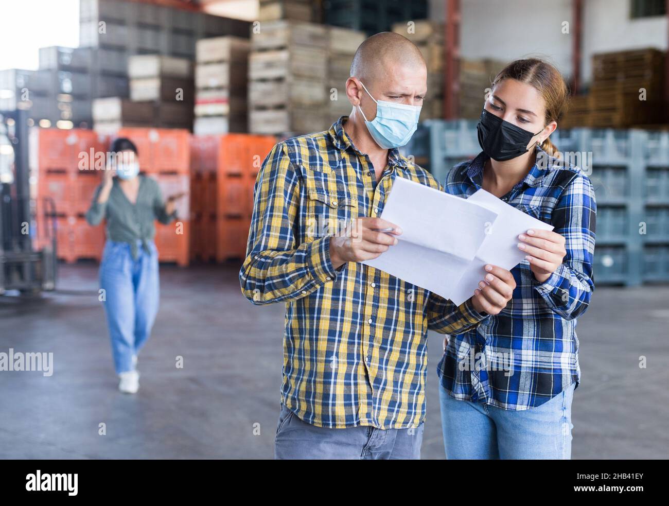 Man and young woman in masks talking about documentation Stock Photo - Alamy
