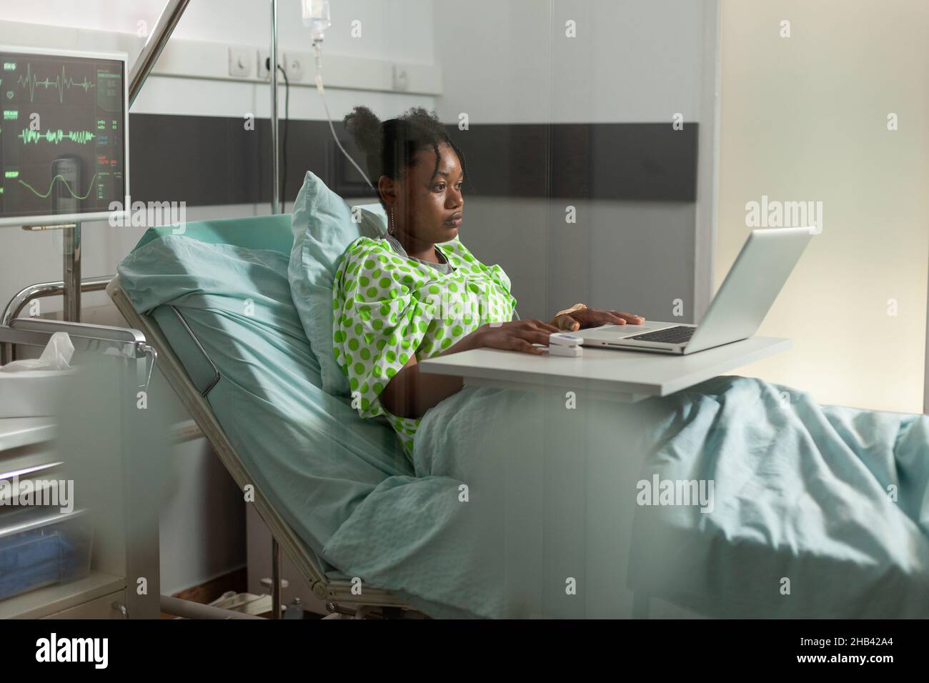 African american sick patient resting in bed watching online comedy ...