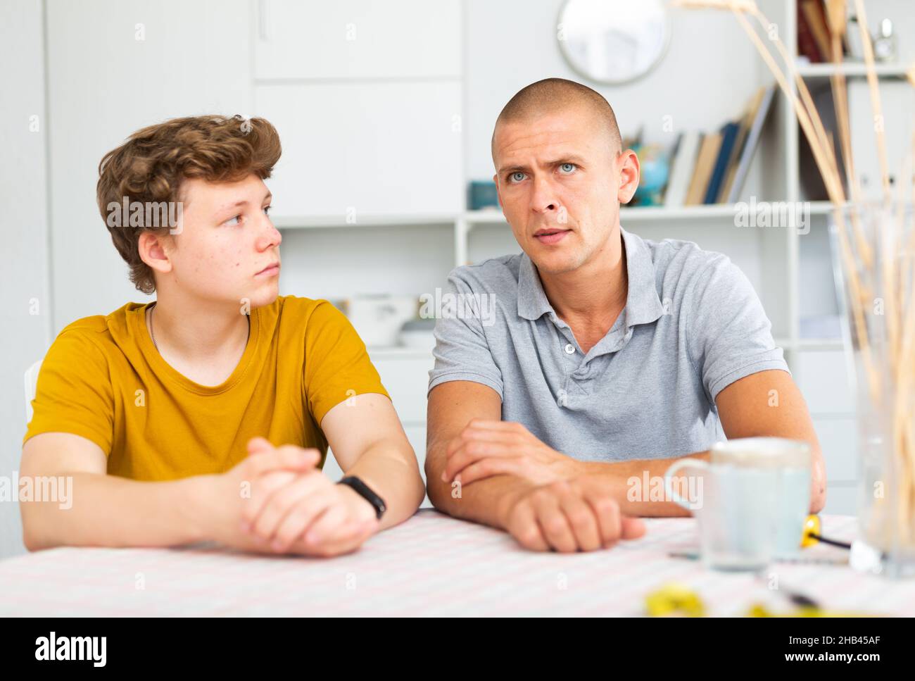 Portrait of teen boy having conversation with man in home Stock Photo ...