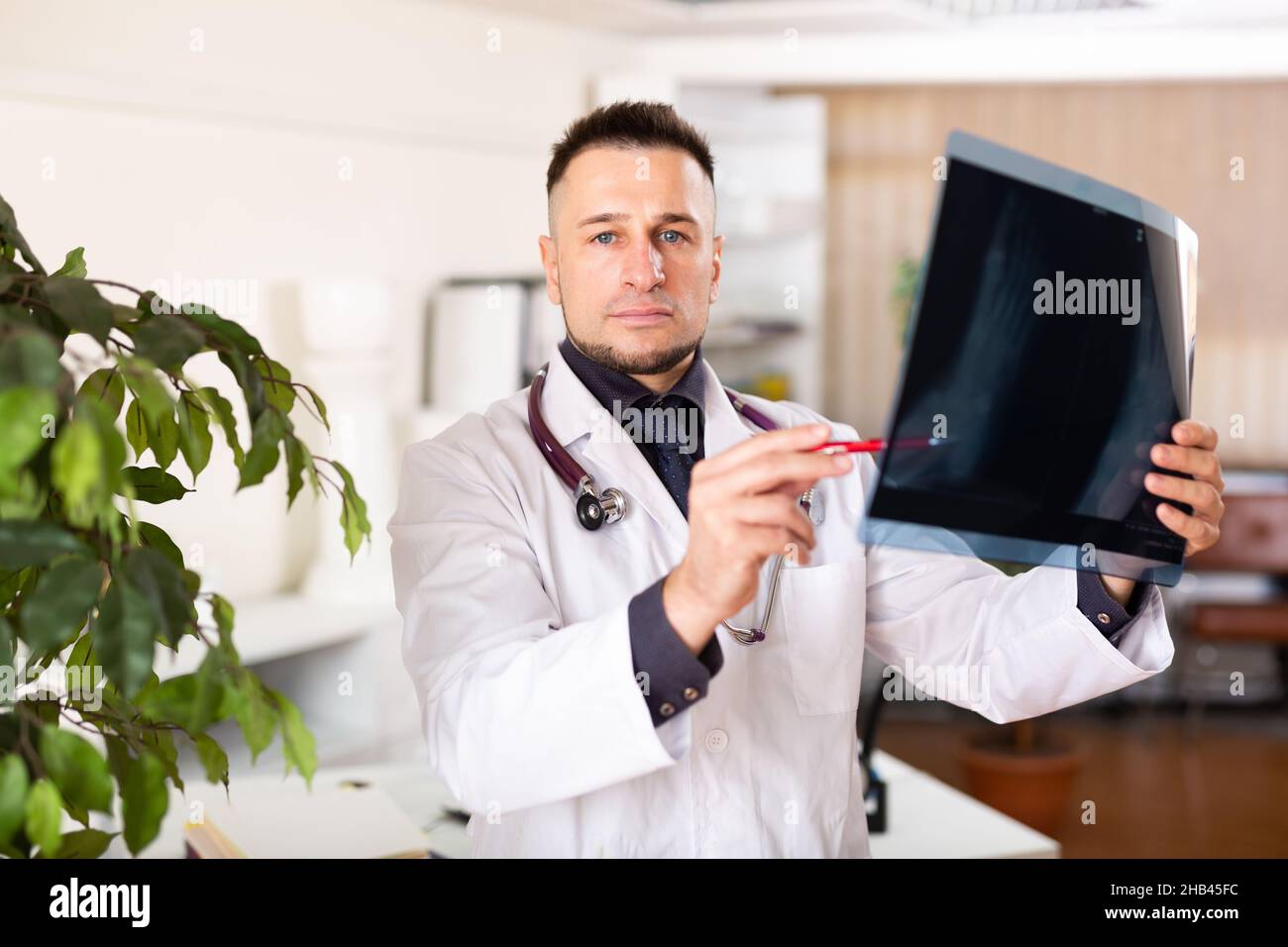 Male doctor examining x-ray closely in clinic Stock Photo - Alamy
