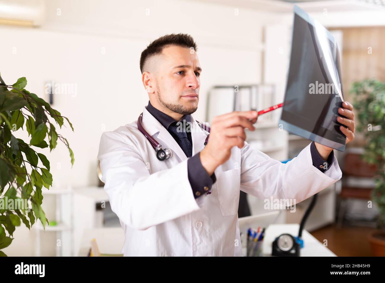 Male doctor examining x-ray closely in clinic Stock Photo - Alamy