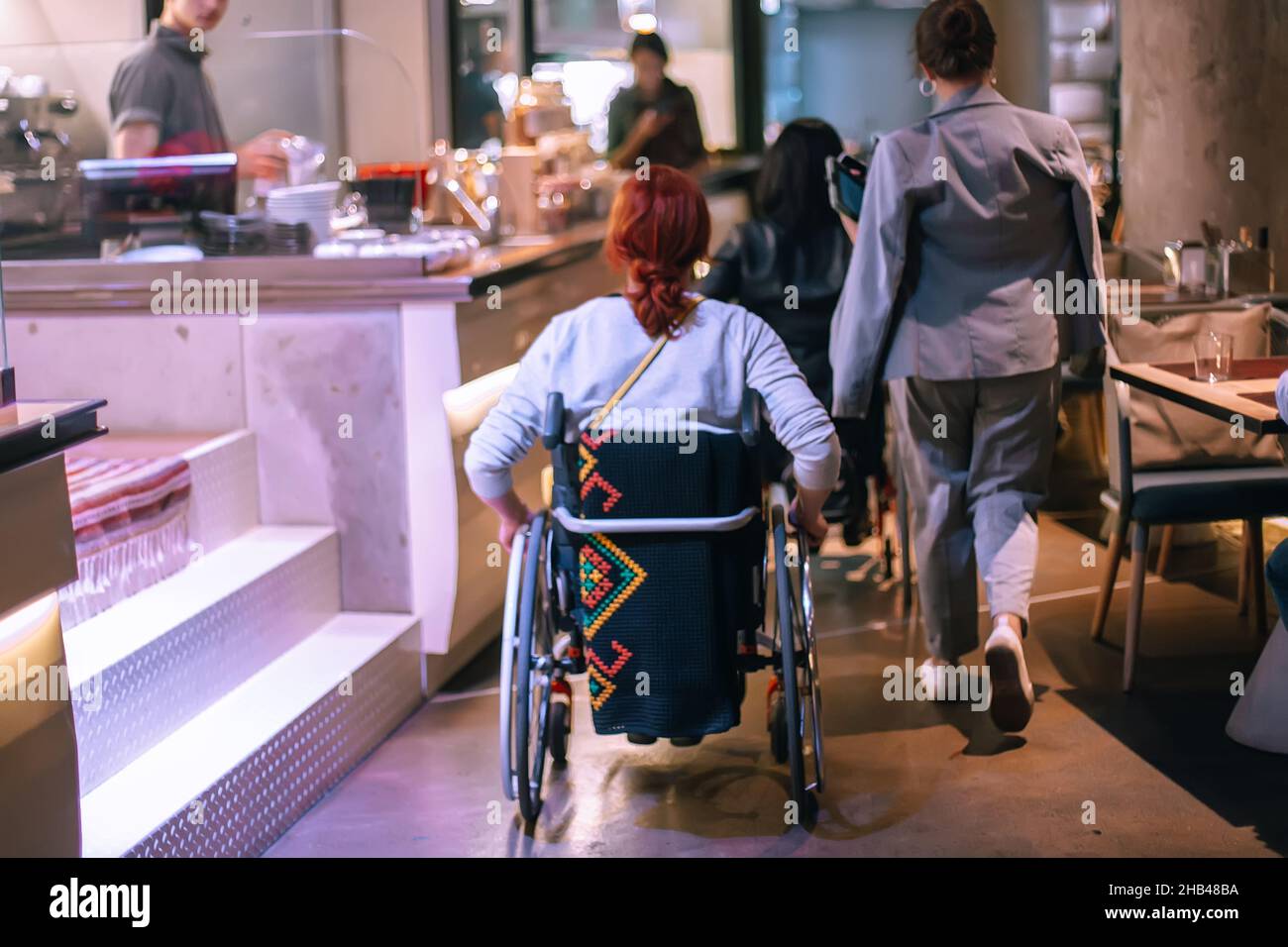 girl in a wheelchair in a cafe near bar. Accessible cafe for people ...