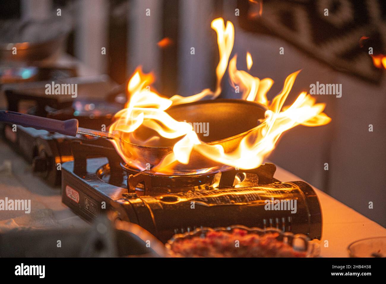 Copper pan engulfed in flames on cooking burner at outdoor resort ...