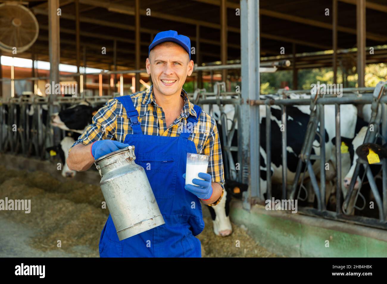 Farmer with milk can in cowhouse Stock Photo - Alamy
