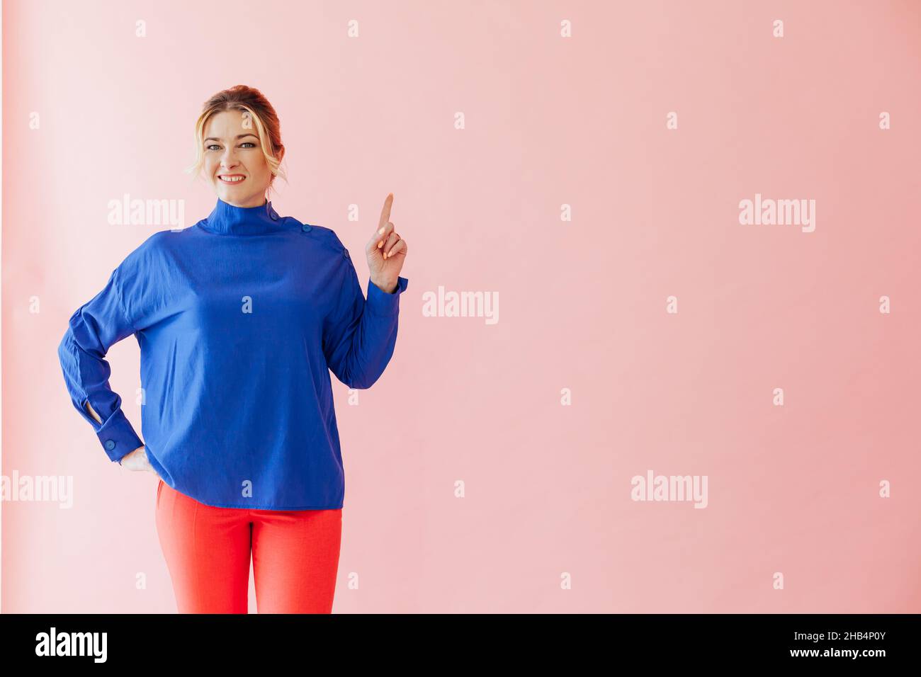 a woman shows her hand direction on a pink background Stock Photo - Alamy