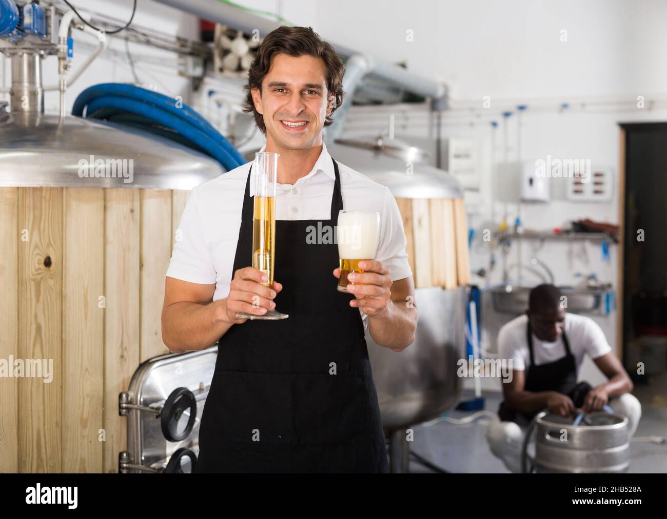 Man brewer in uniform is standing with glass of beer and flask Stock ...