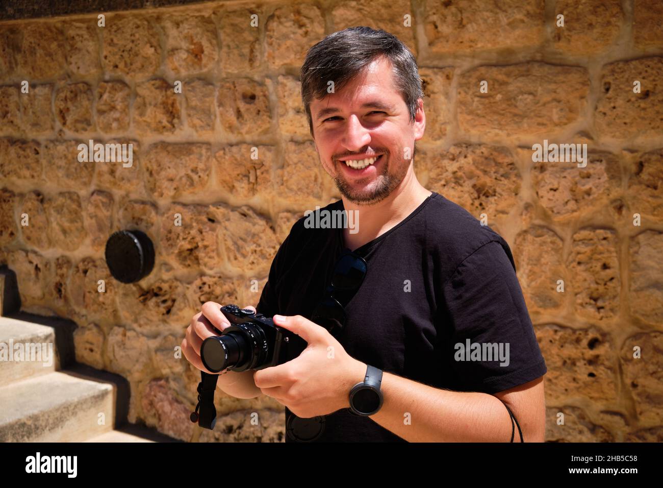 Smiling tourist stands holding camera Stock Photo - Alamy