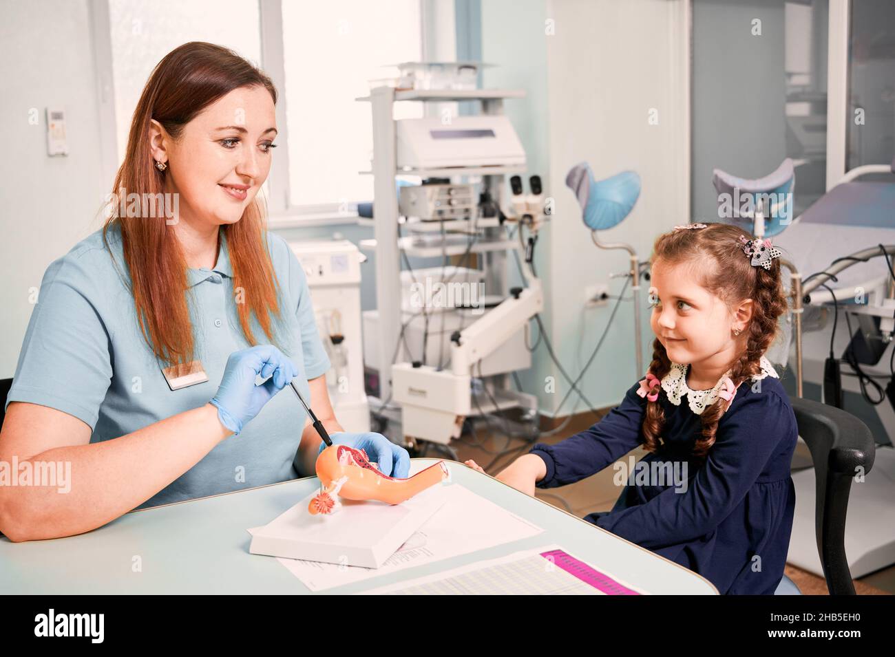 Child looking at gynecologist while doctor pointing at uterus ...