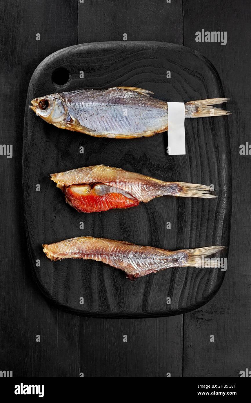 Whole and skinned salted air-dried roach fish with caviar on black ...