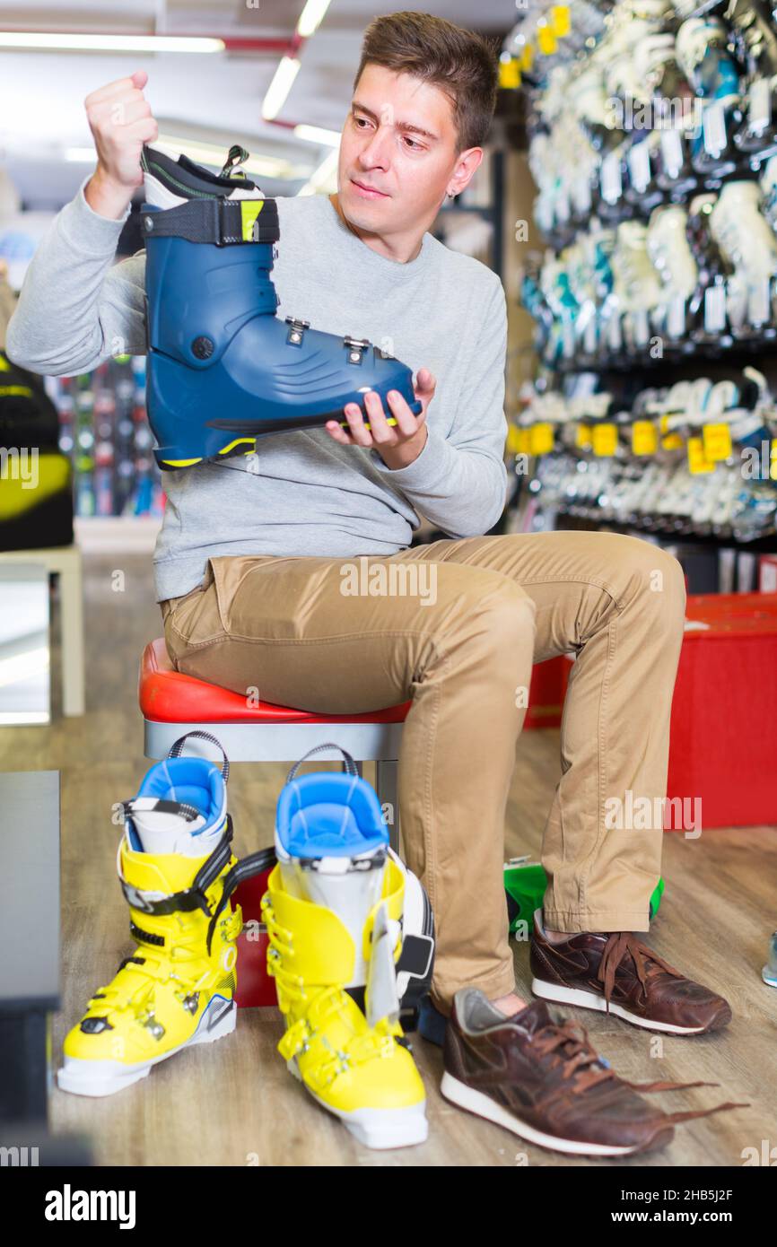 Customer male is trying on boots for skiing Stock Photo - Alamy