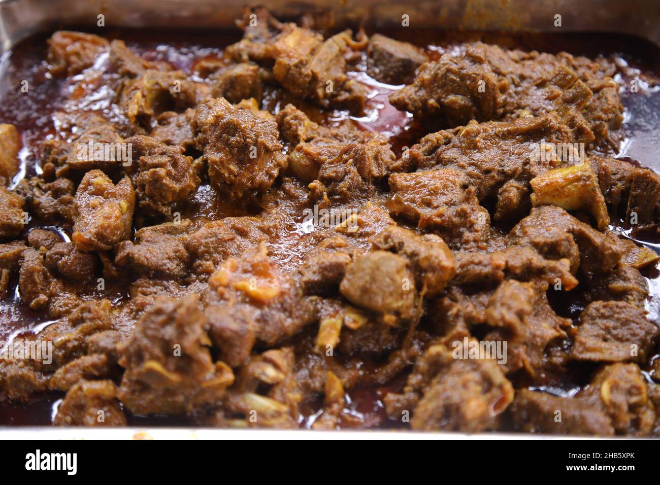 Grilled mutton in a serving plate on a wooden table with a black ...