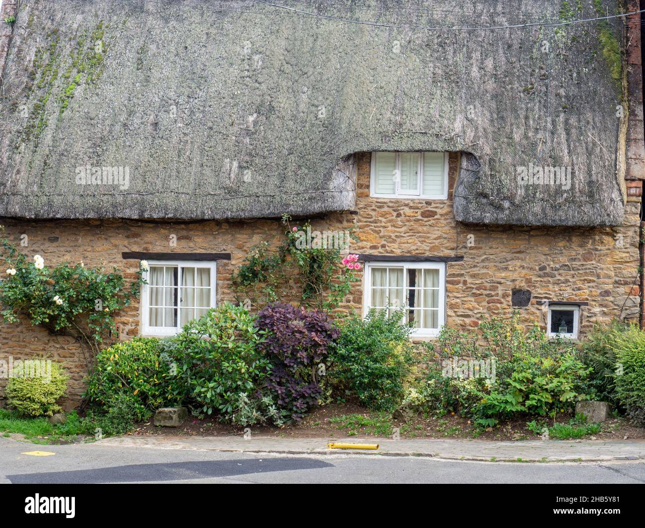 Frontage of an attractive stone built thatched cottage in winter in the ...