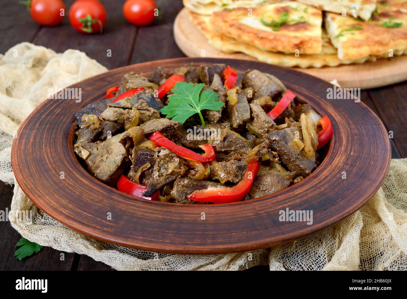 Pieces of fried liver with onions and fresh bell peppers on a plate ...
