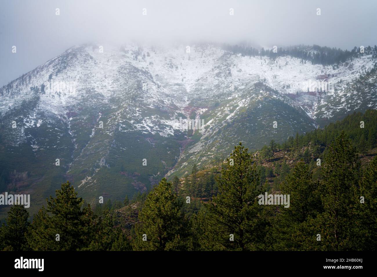 Tall snowy mountain in the countryside with dense fog blocking the ...