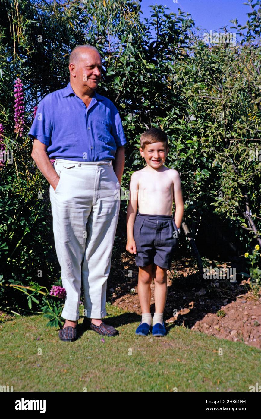 Family portrait full length grandfather and grandson standing in garden ...