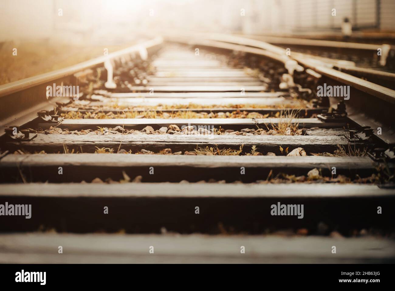 Empty old railway rails with wooden sleepers, illuminated by sunlight ...